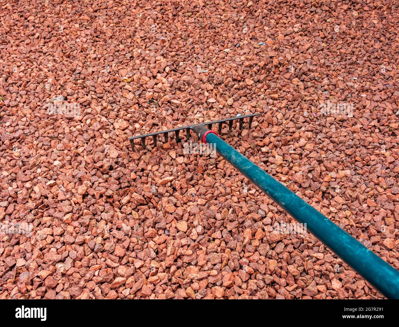 Rake with blue pole drawing the red expanded clay gravel Stock Photo ...