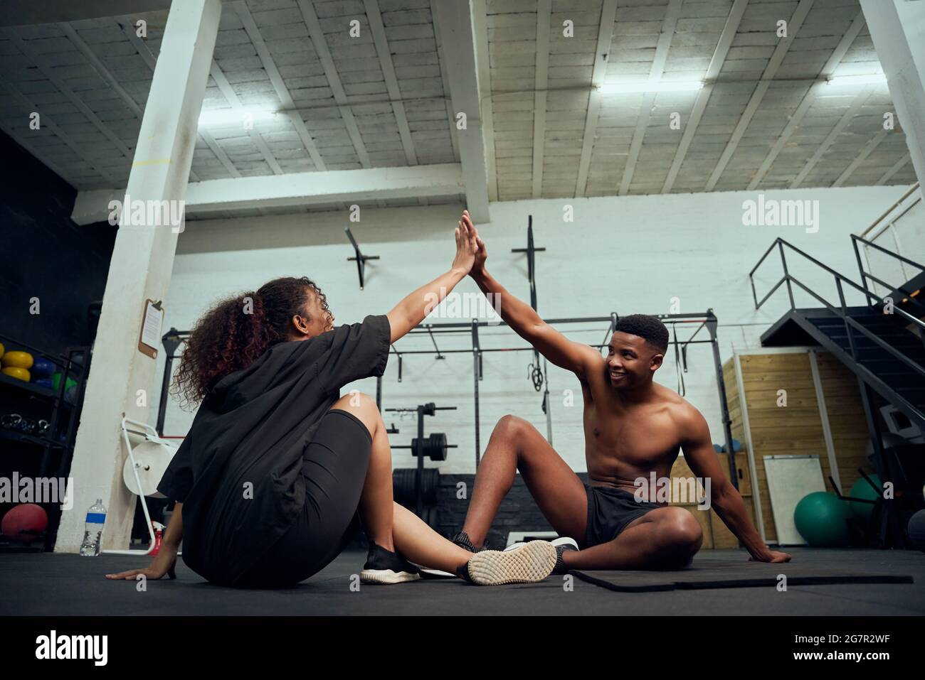 Mixed race friends doing cross fit in the gym. Male personal trainer ...