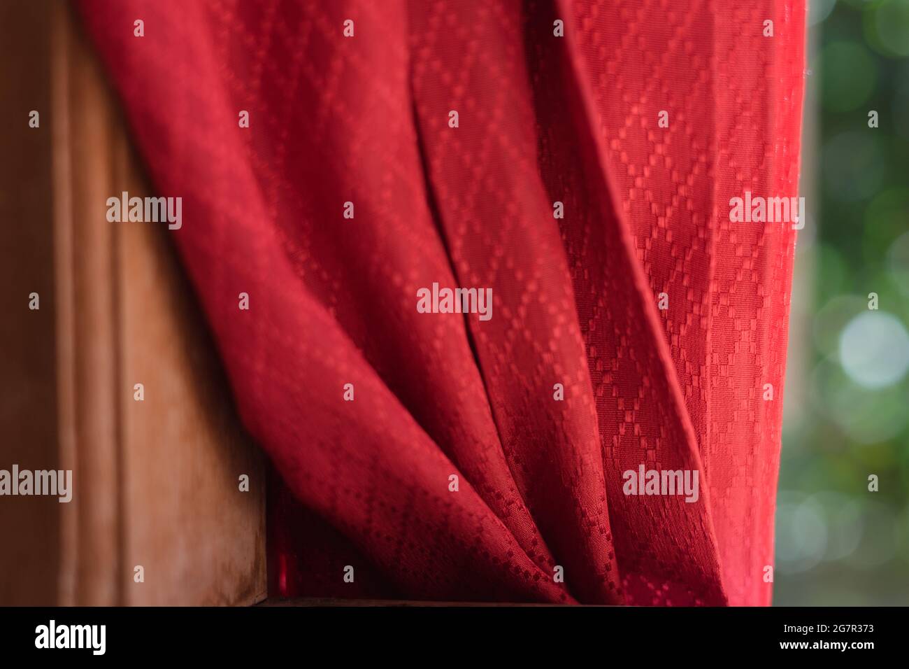 Shallow depth of field of a folded red curtain with wooden frame on a ...