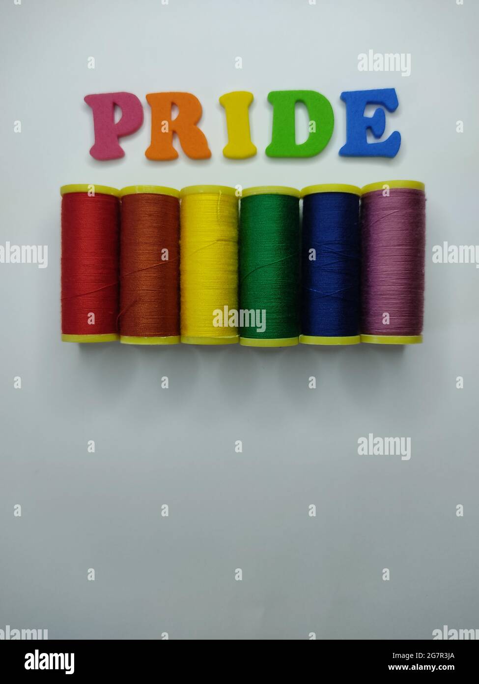 Vertical text PRIDE next to sewing threads in pride colors isolated on white background Stock ...