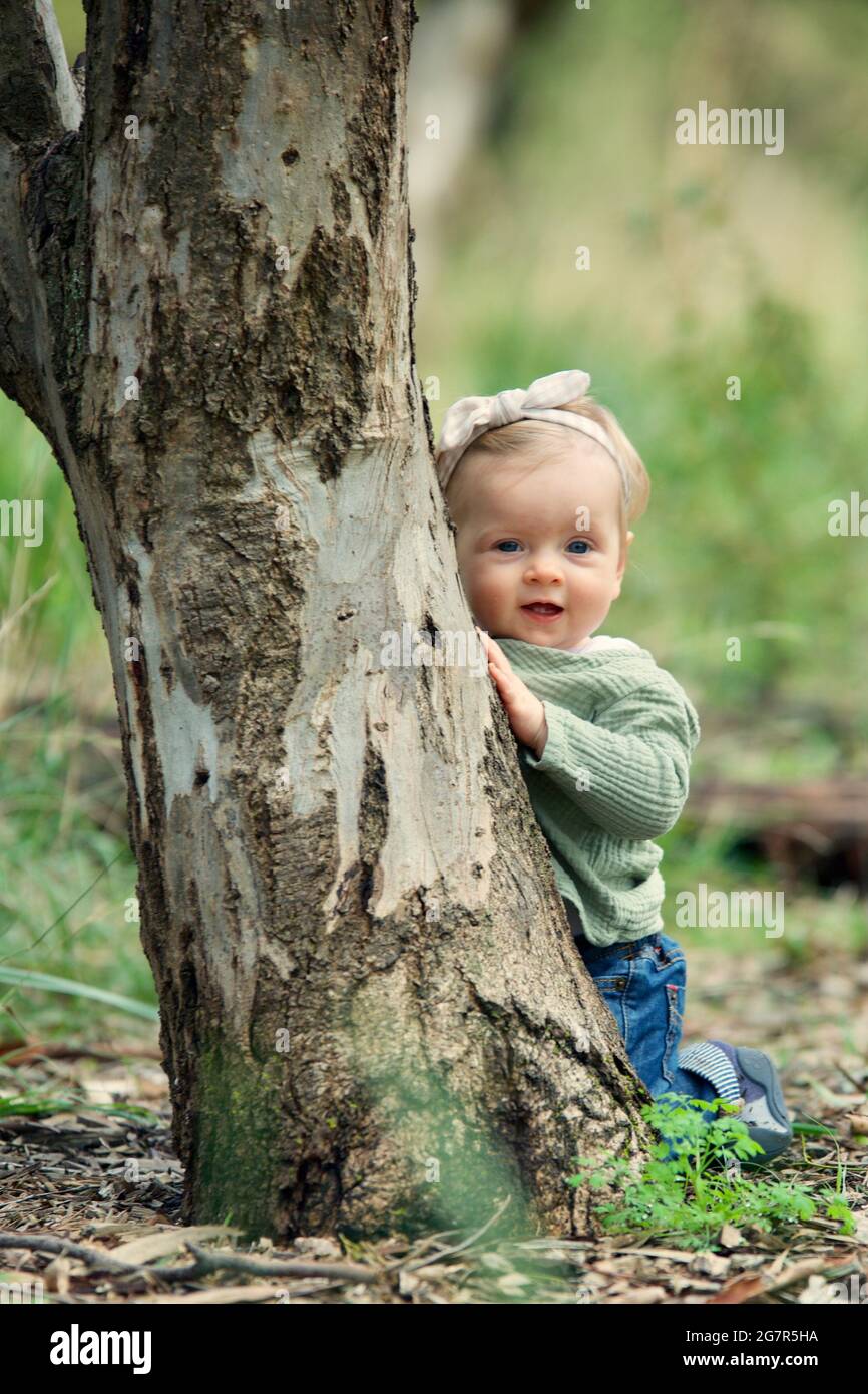 Little girl playing behind a tree hi-res stock photography and images ...