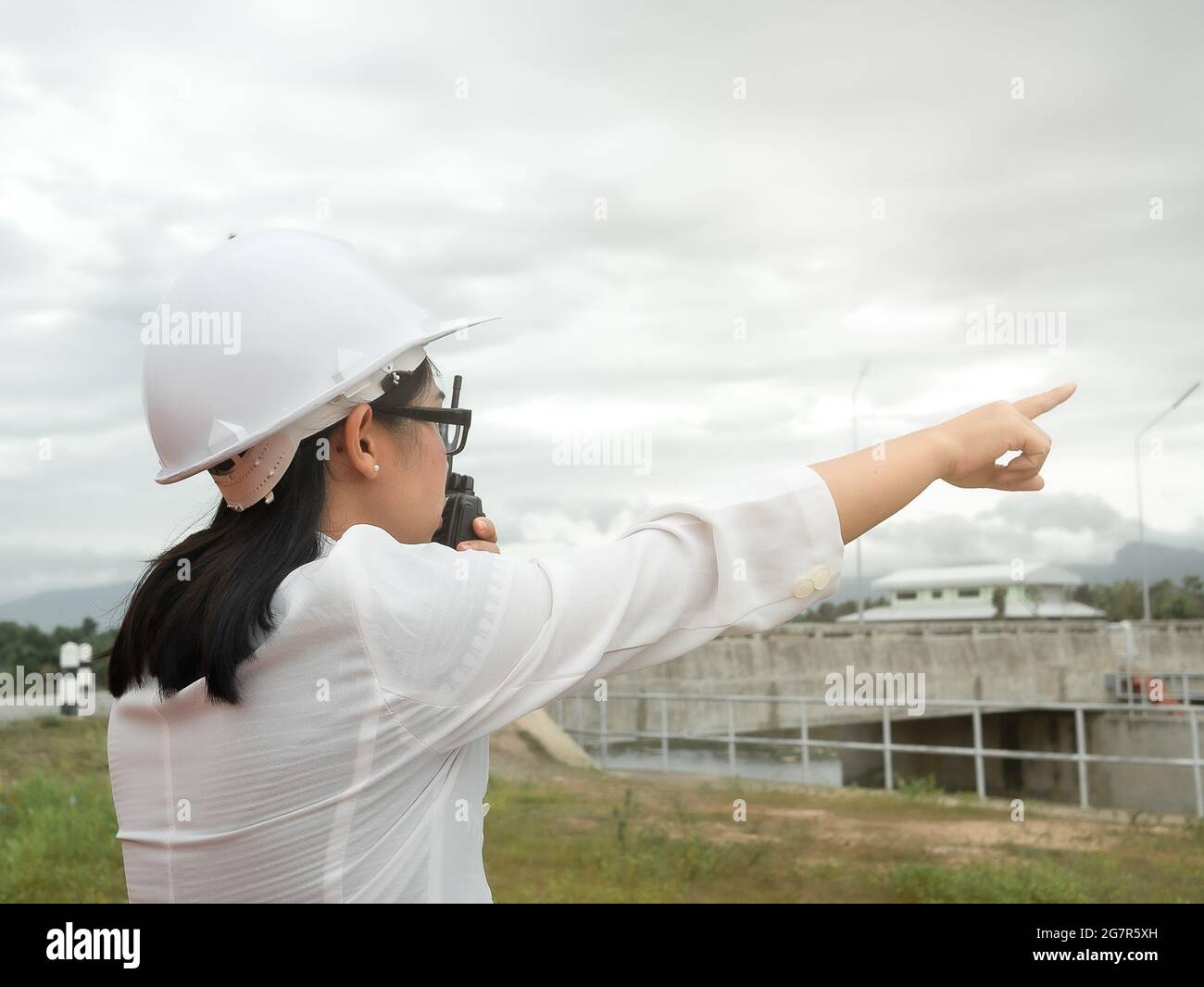 Female engineer in a white helmet using radio communication with ...