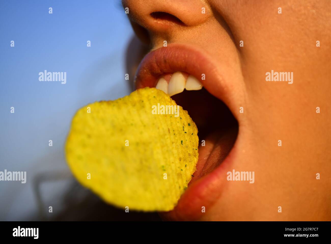 Pleasure eating potato chips. Close up female mouth eat potato chips ...