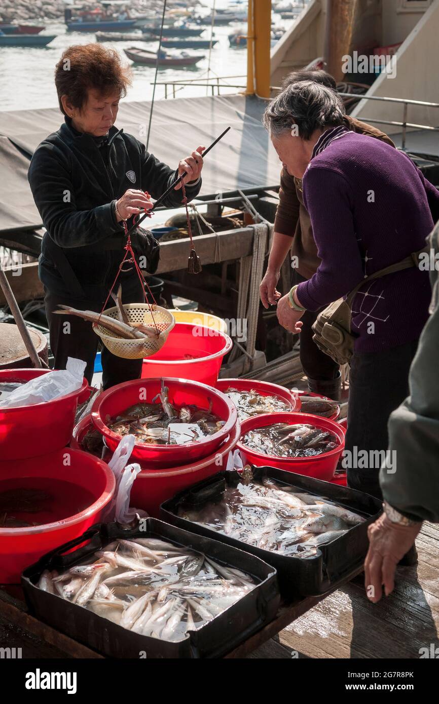 A fisherman's wife uses a traditional Chinese balance scale to weigh a ...