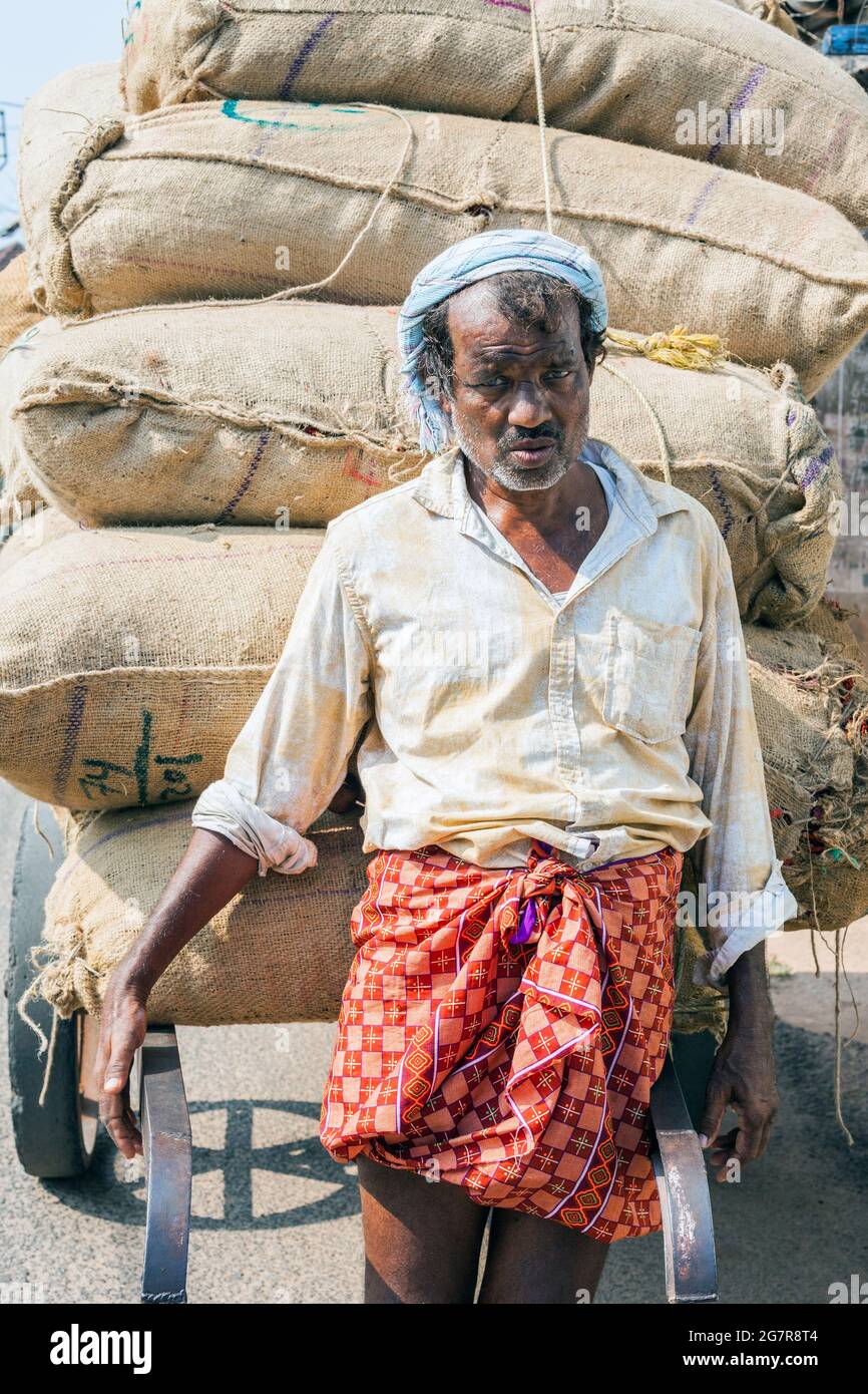 Indian male porter pulling heavy wagon load of sacks in Fort Kochi ...