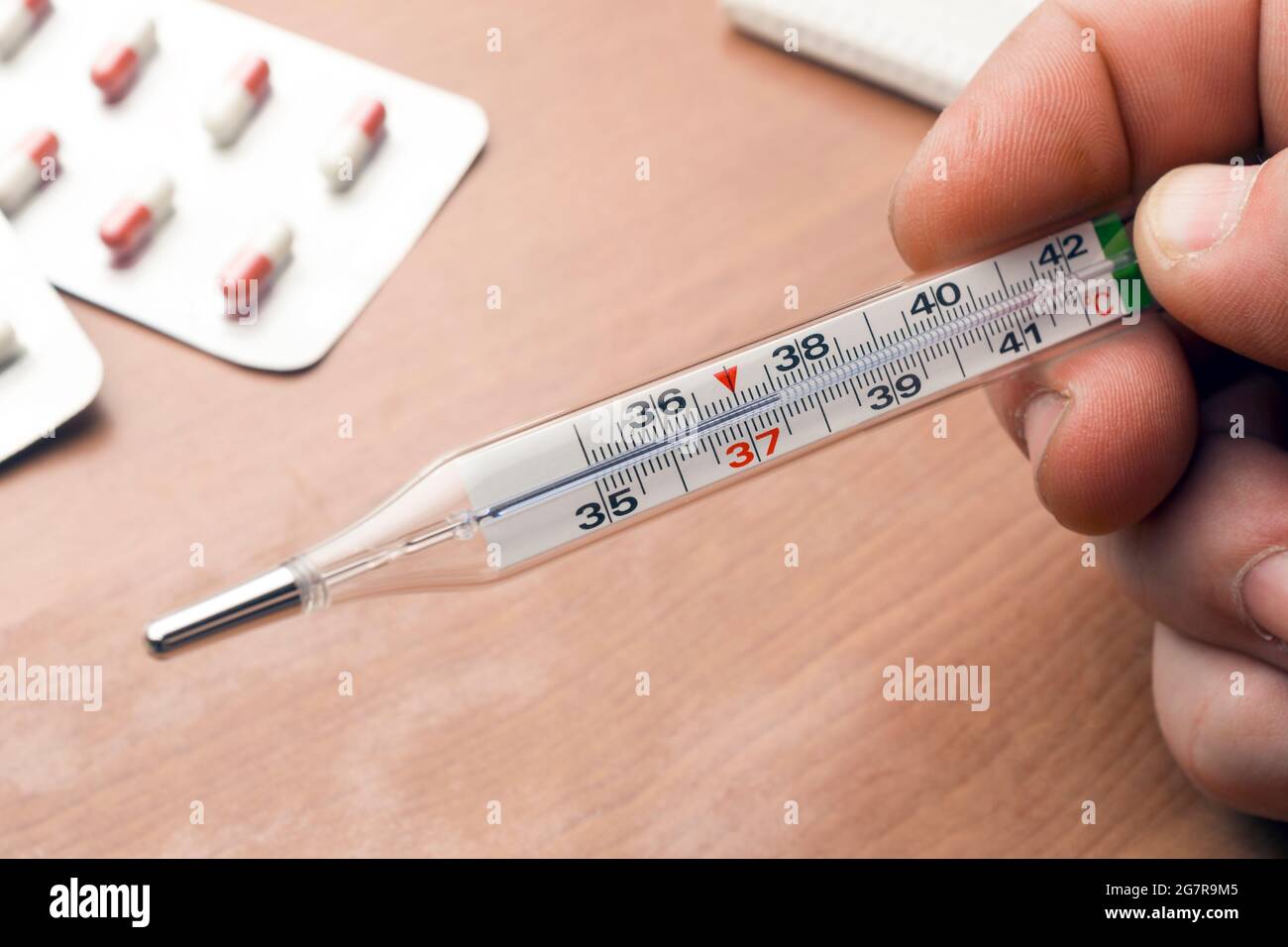 Man checks his body temperature using a mercury in glass thermometer ...