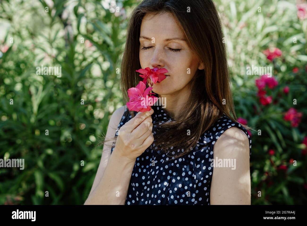 Spanish girl sniffing pink roses Stock Photo - Alamy