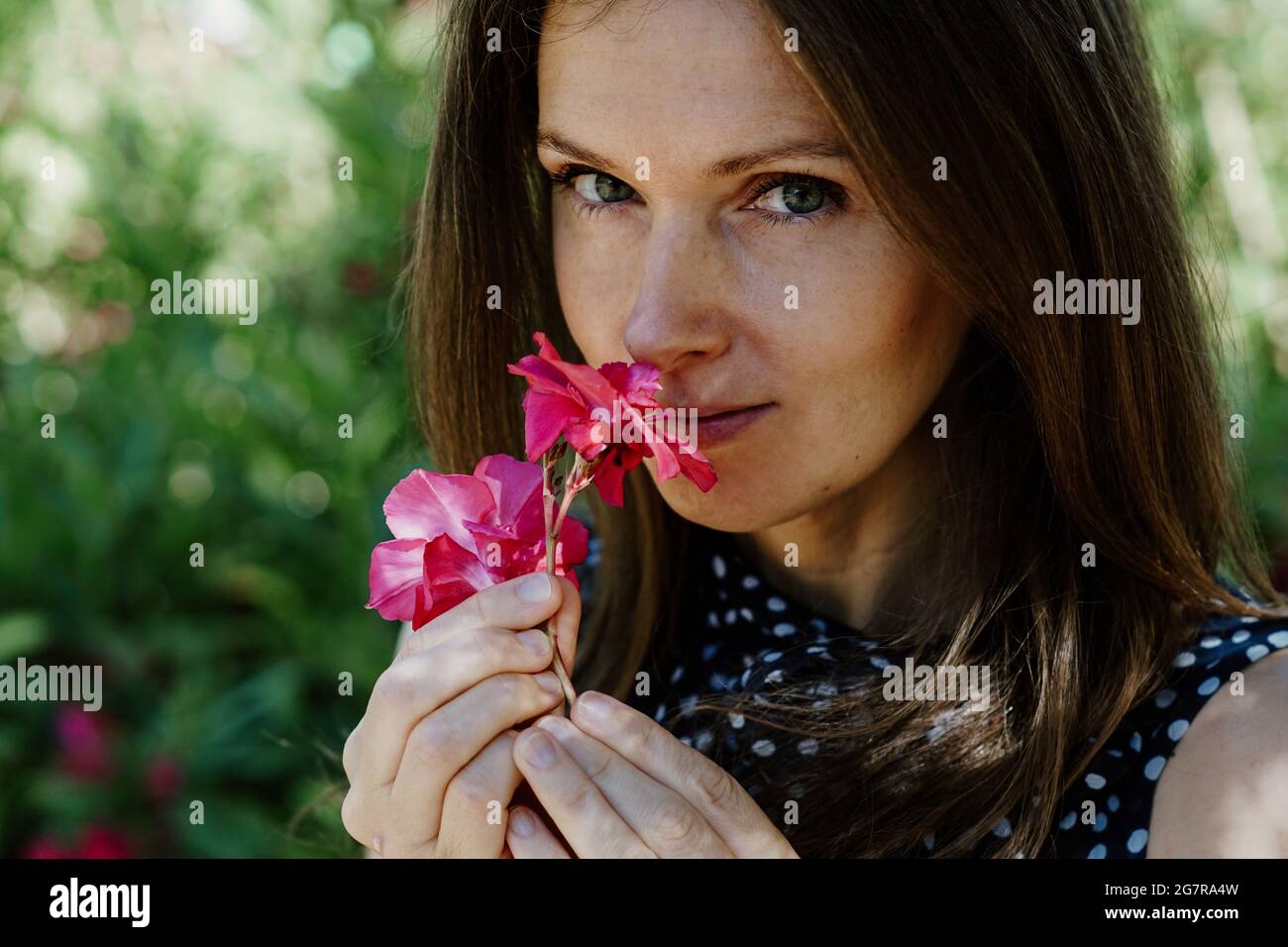 Spanish girl sniffing pink roses Stock Photo - Alamy