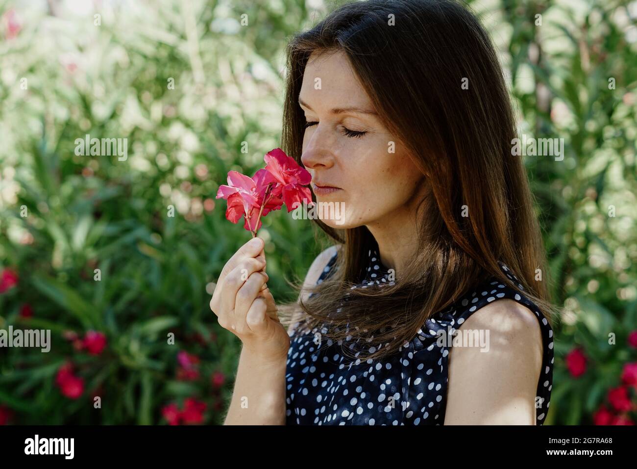 Spanish girl sniffing pink roses Stock Photo - Alamy