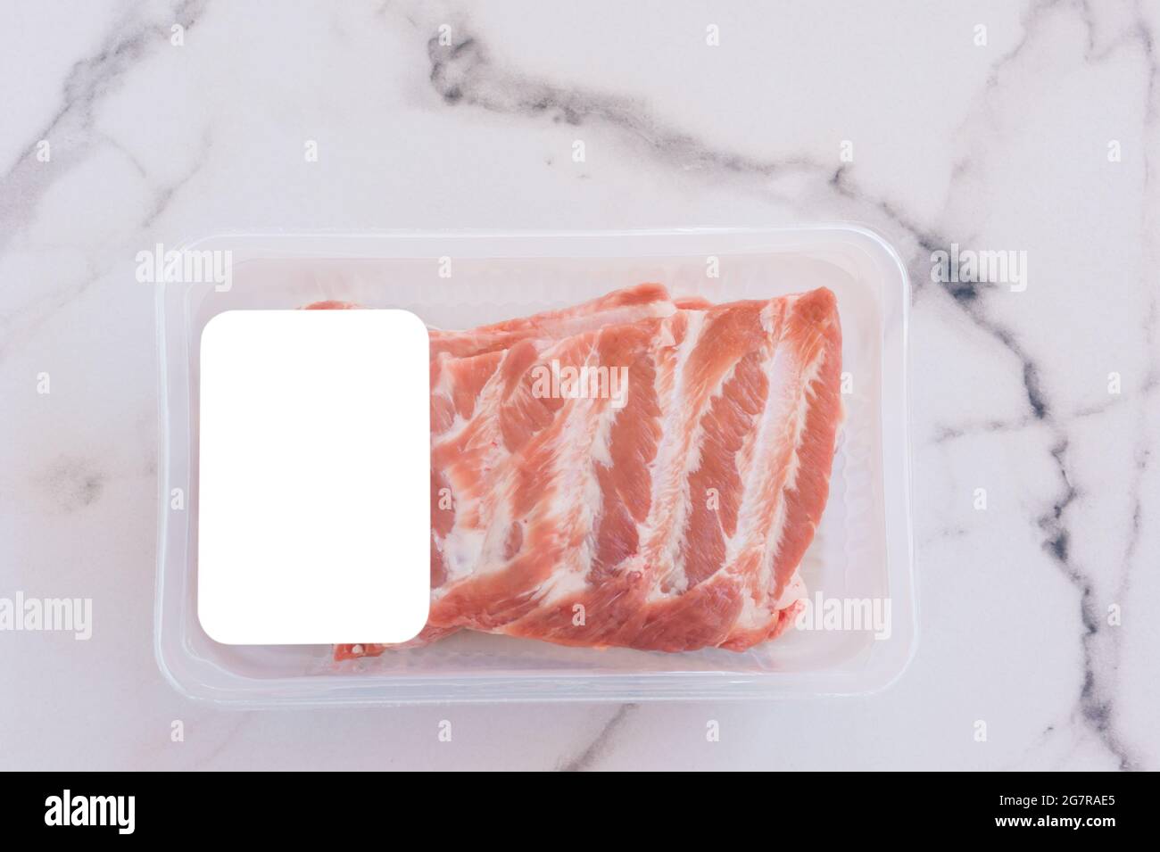 Raw pork ribs in vacuum packaging on marble background, logo mockup for ...