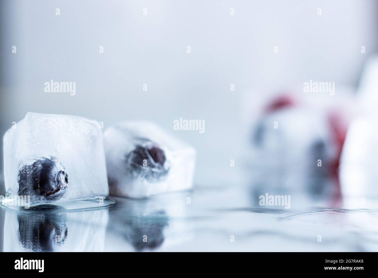 Close up of raspberries and blueberries frozen in ice cube with ...