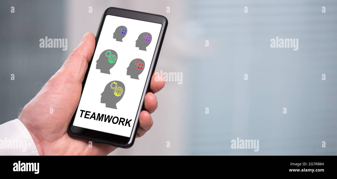 Hand holding a smartphone with teamwork concept Stock Photo - Alamy