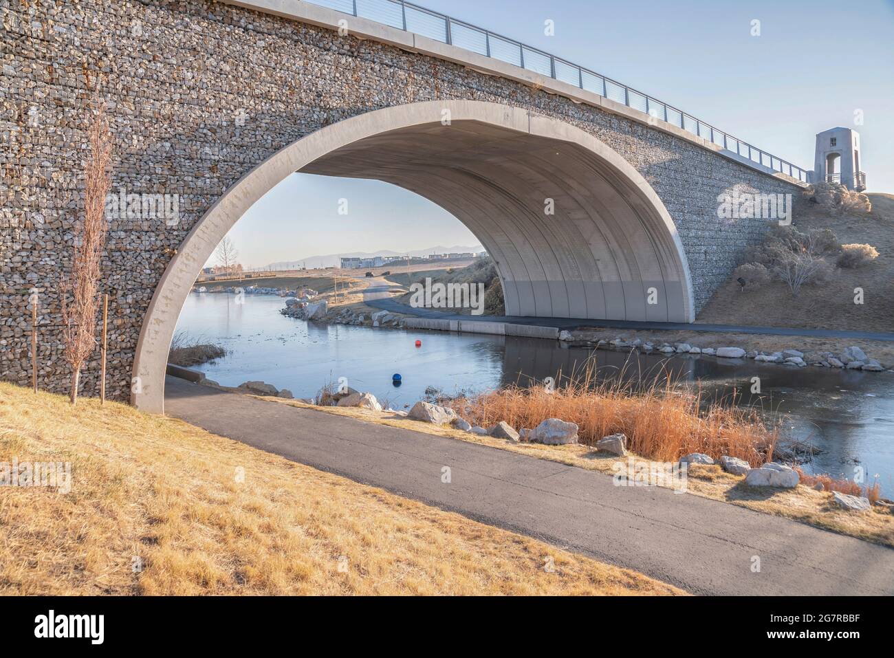 Two trail paths on both sides of the lake under an arched bridge with ...