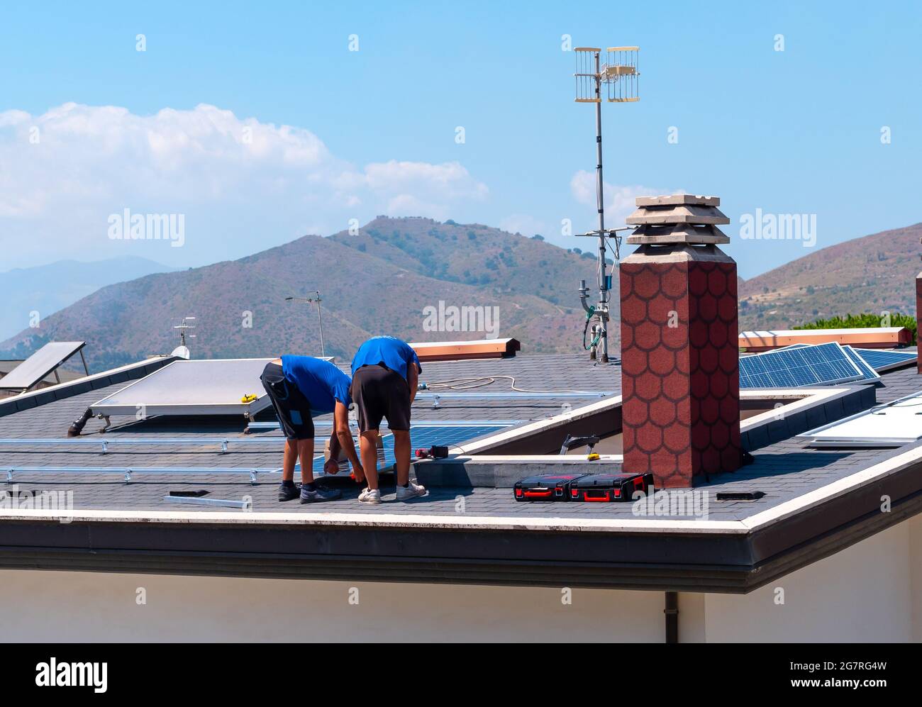 Installation of a photovoltaic system on the roof of a house. Workers ...
