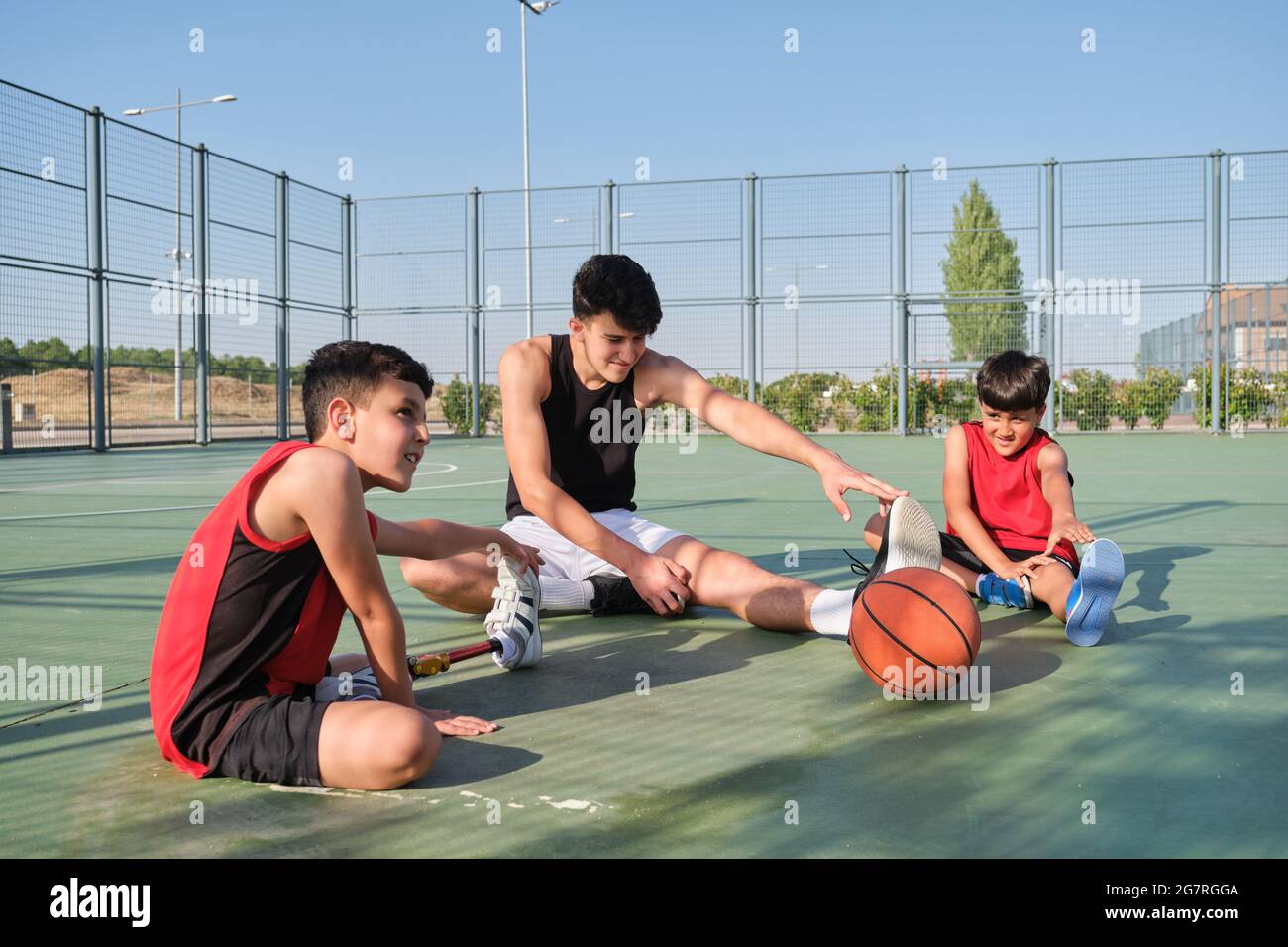 Three brothers doing leg stretching exercises, one of them has a leg ...