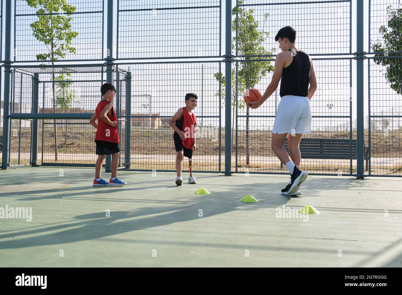 Basketball coach giving a basketball to a leg prosthesis student ...