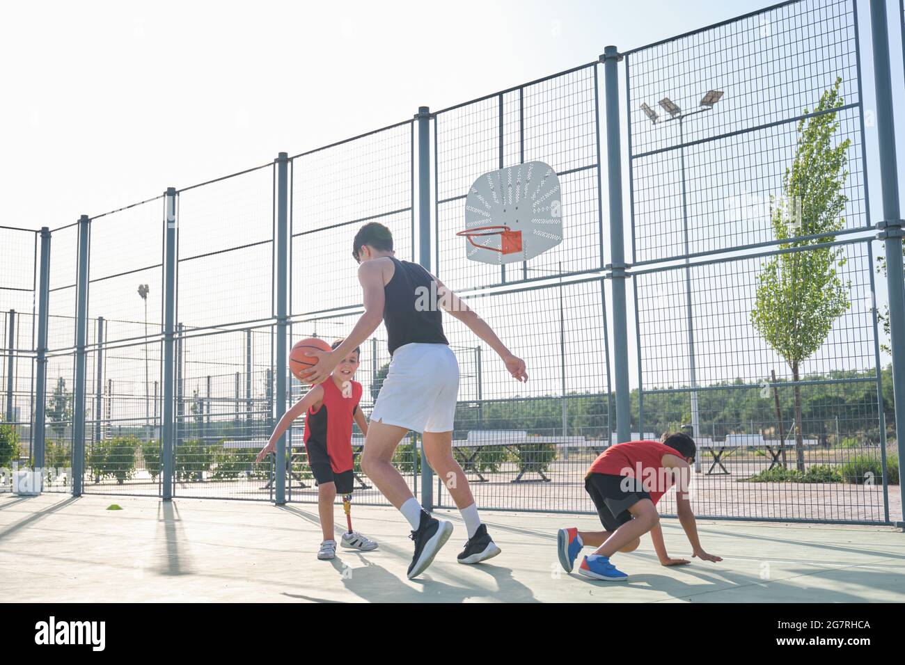 Basketball trainer playing basketball with two children, one of them ...