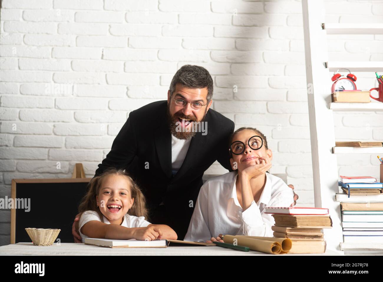 Portrait of happy father and school kids daughters at school. Reading ...