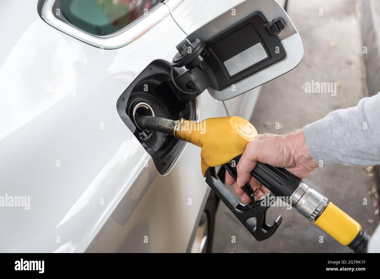 Hand holding yellow fuel pump nozzle and refilling car Stock Photo - Alamy