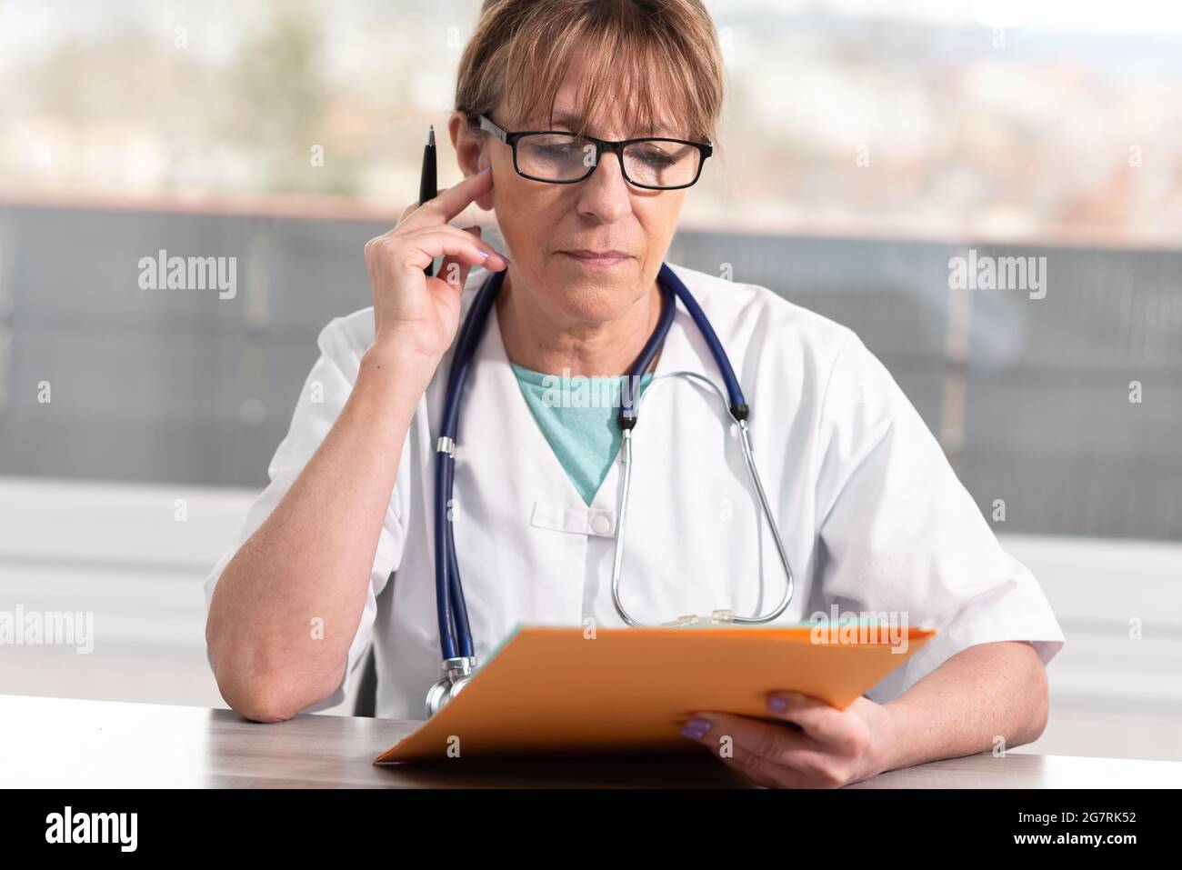 Female doctor reading a medical report in office Stock Photo - Alamy