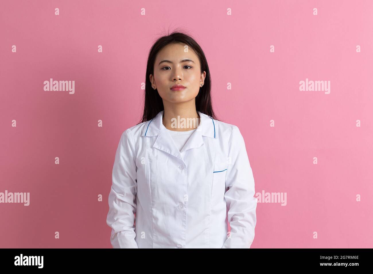 Asian korean positive doctor woman in white medical gown against pink ...