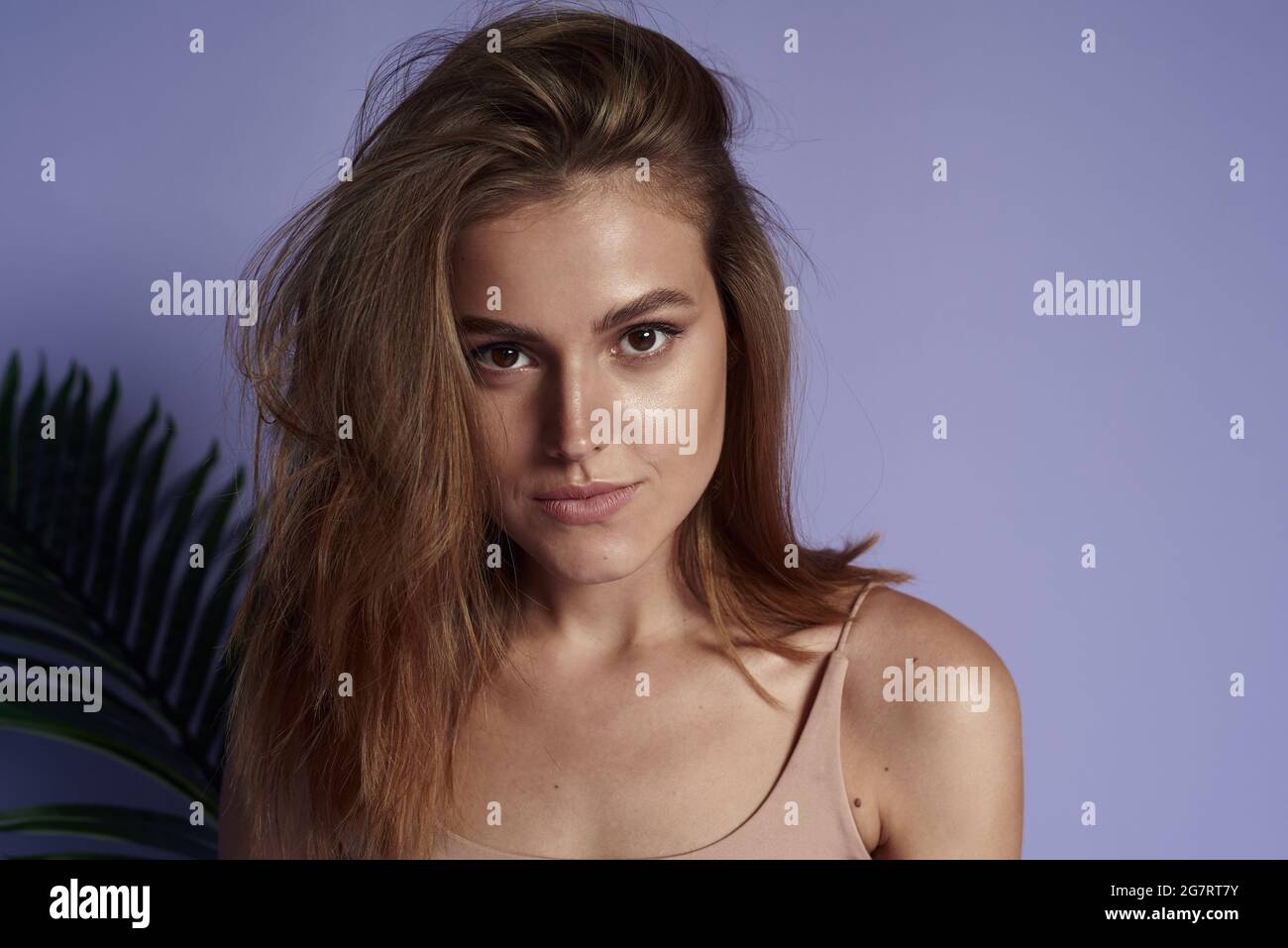 Pretentious, serious female model in a purple studio with a tropical ...