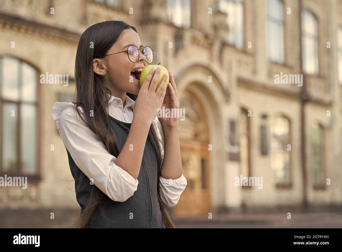 Happy child in uniform eat vitamin apple during school break outdoors ...