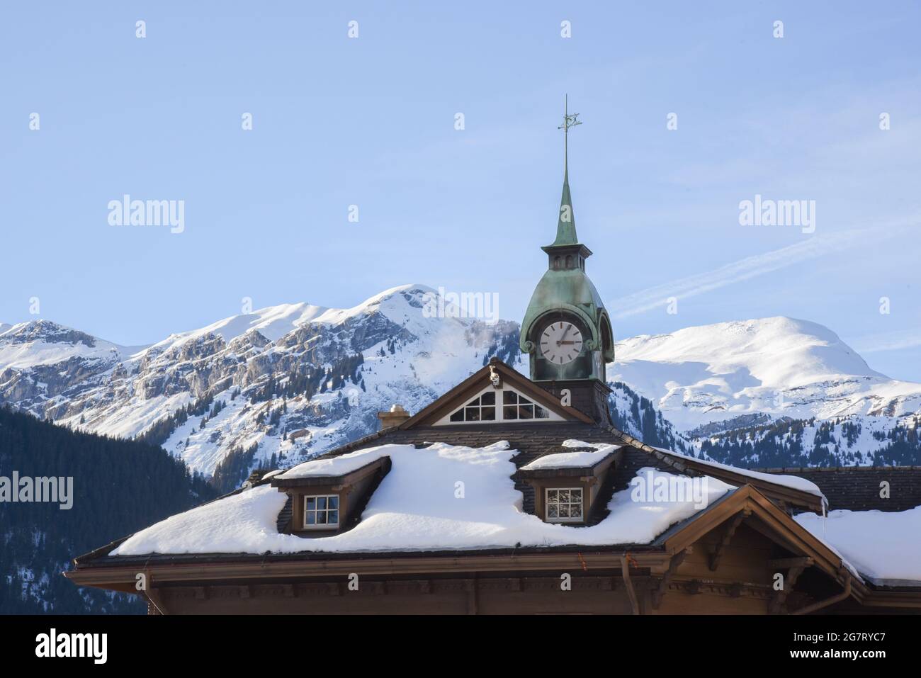 Small clock tower in village surrounded by snowy Swiss alps in ...