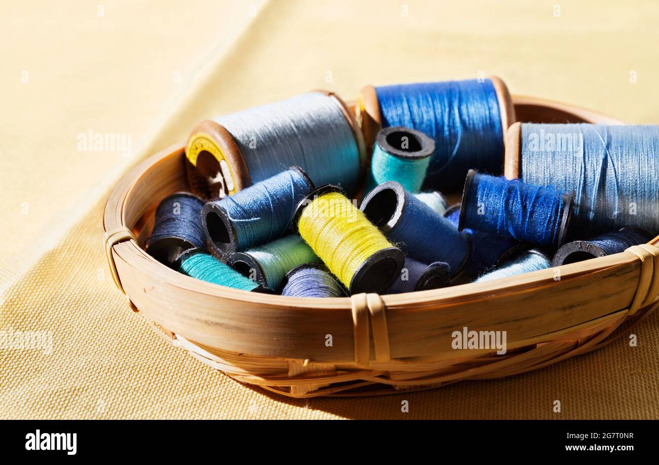 Spools of blue thread and one yellow spool in basket ,different size ...