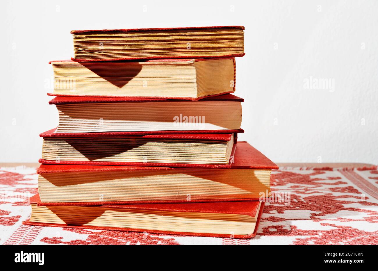 Stack of books with red covers on table with colored tablecloth Stock ...