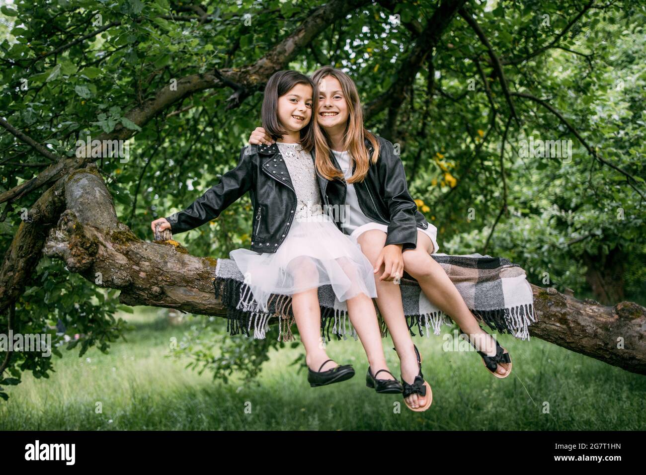 Beautiful little ladies hugging each other while sitting together on ...