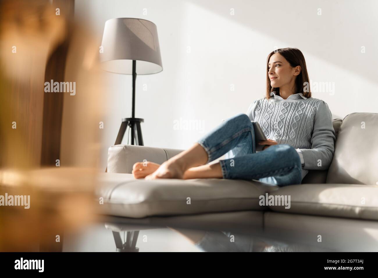 Smiling middle aged woman using digital tablet while relaxing on a ...