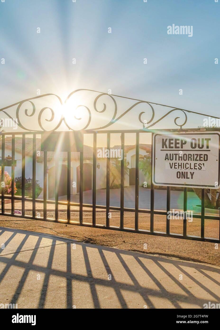 Vertical Iron gate against houses and ocean view with bright sun in the ...