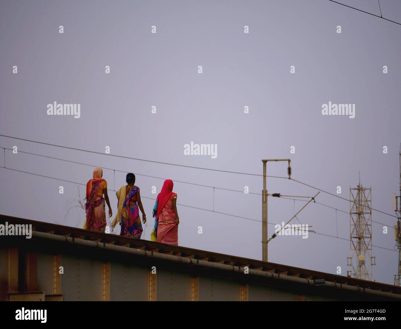 Three indian poor lady going upon railway bridge around industrial ...