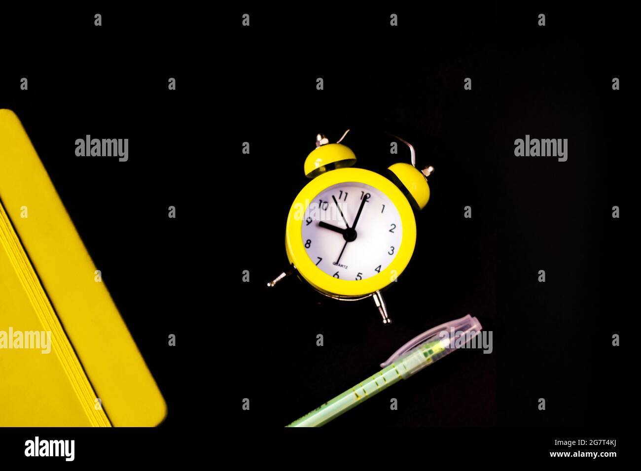 Directly Above Shot Of yellow alarm clock with closed notepad Diary on ...