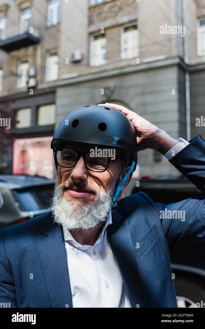 mature businessman in blazer adjusting helmet outside Stock Photo - Alamy