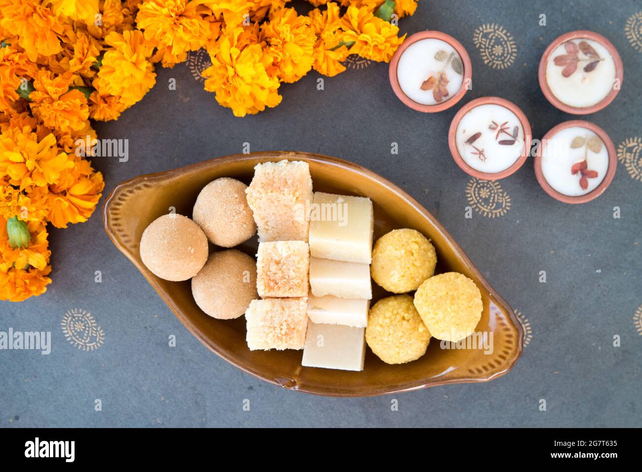 Top view of Indian sweets, Diya lights, and marigold flowers for the ...