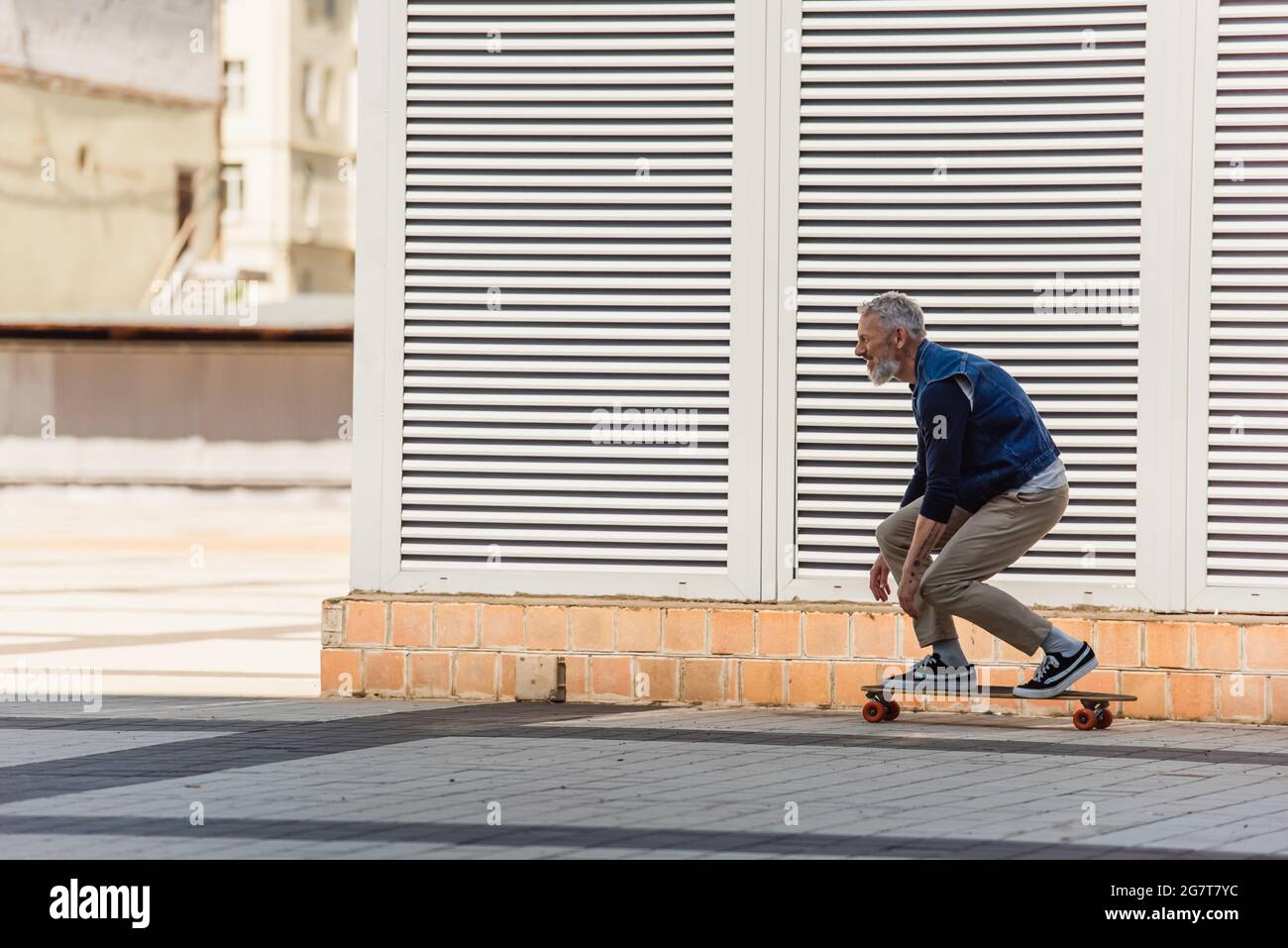 side view of positive and middle aged man riding longboard on urban ...