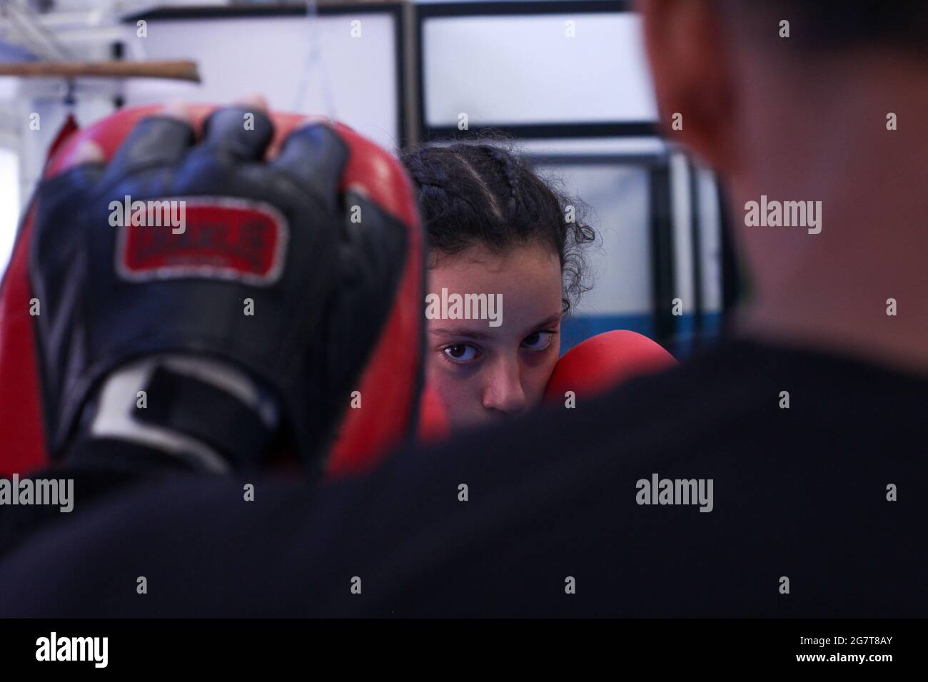 Young Spanish girl training with a professional Hispanic boxer in a gym ...