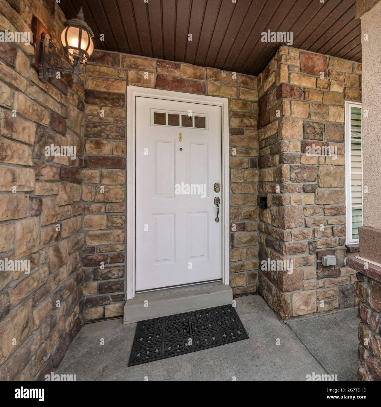 Square frame Front exterior of a house with white door and stone walls ...