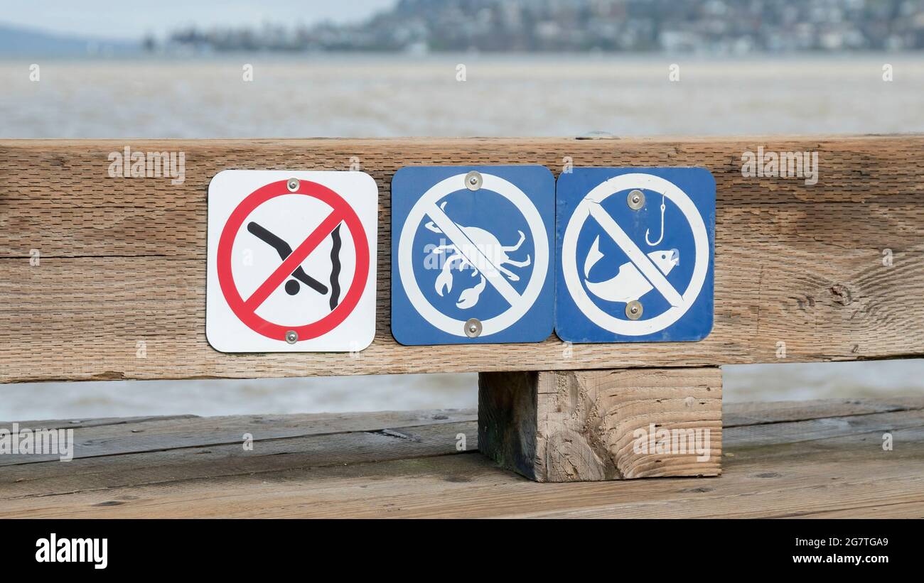 Pano Three signs in a harbor with a blurred background and gray skies ...