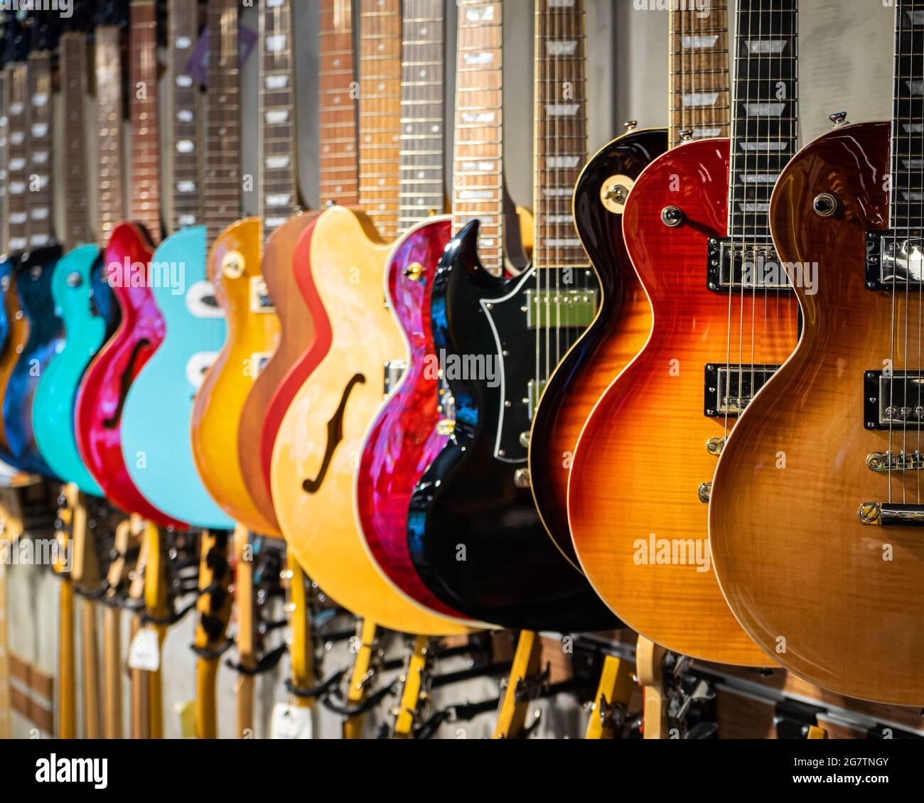Row of acoustic and electric guitars different color in a music ...