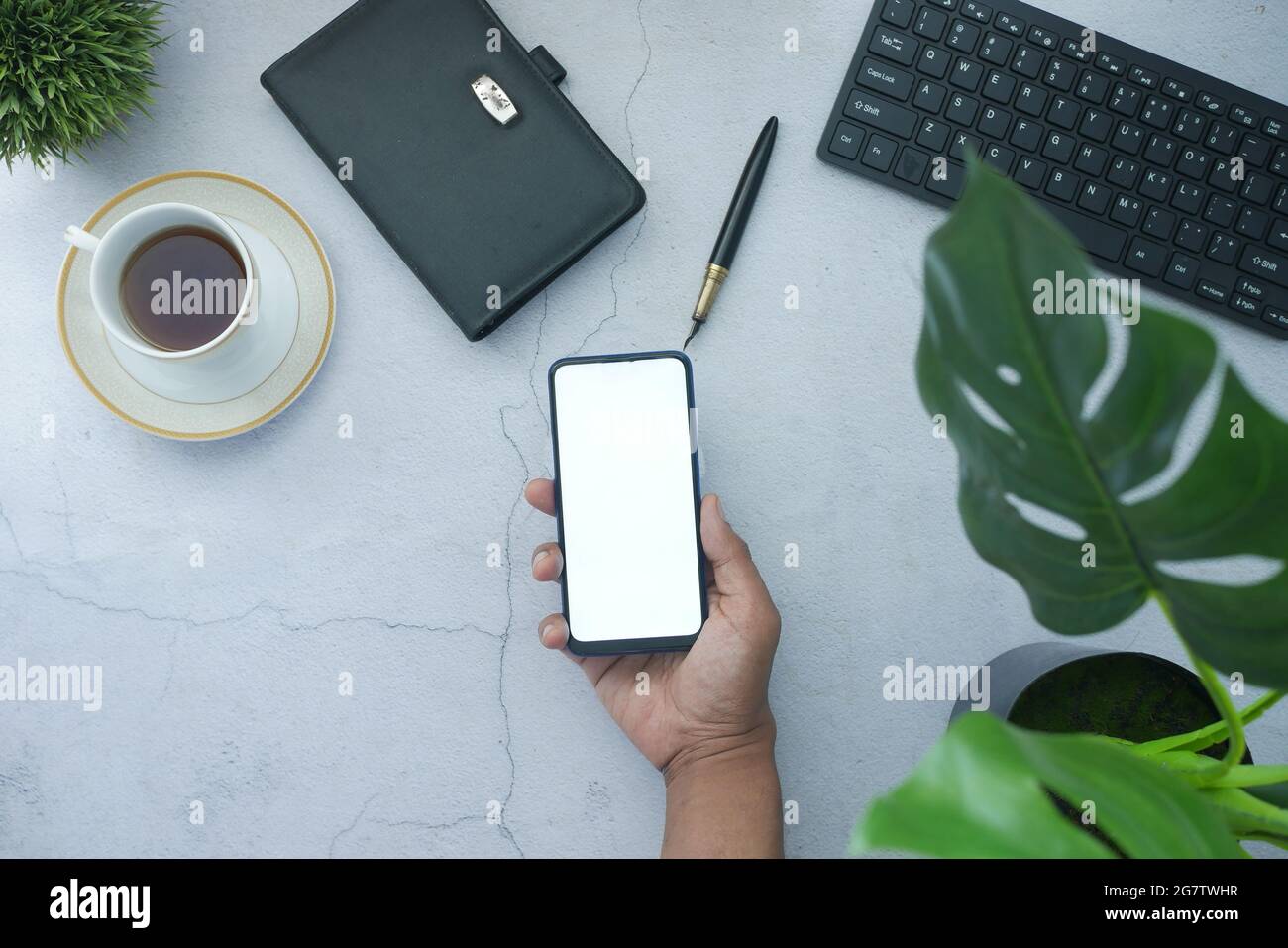 Top view of man hand holding smart phone with empty screen on office ...