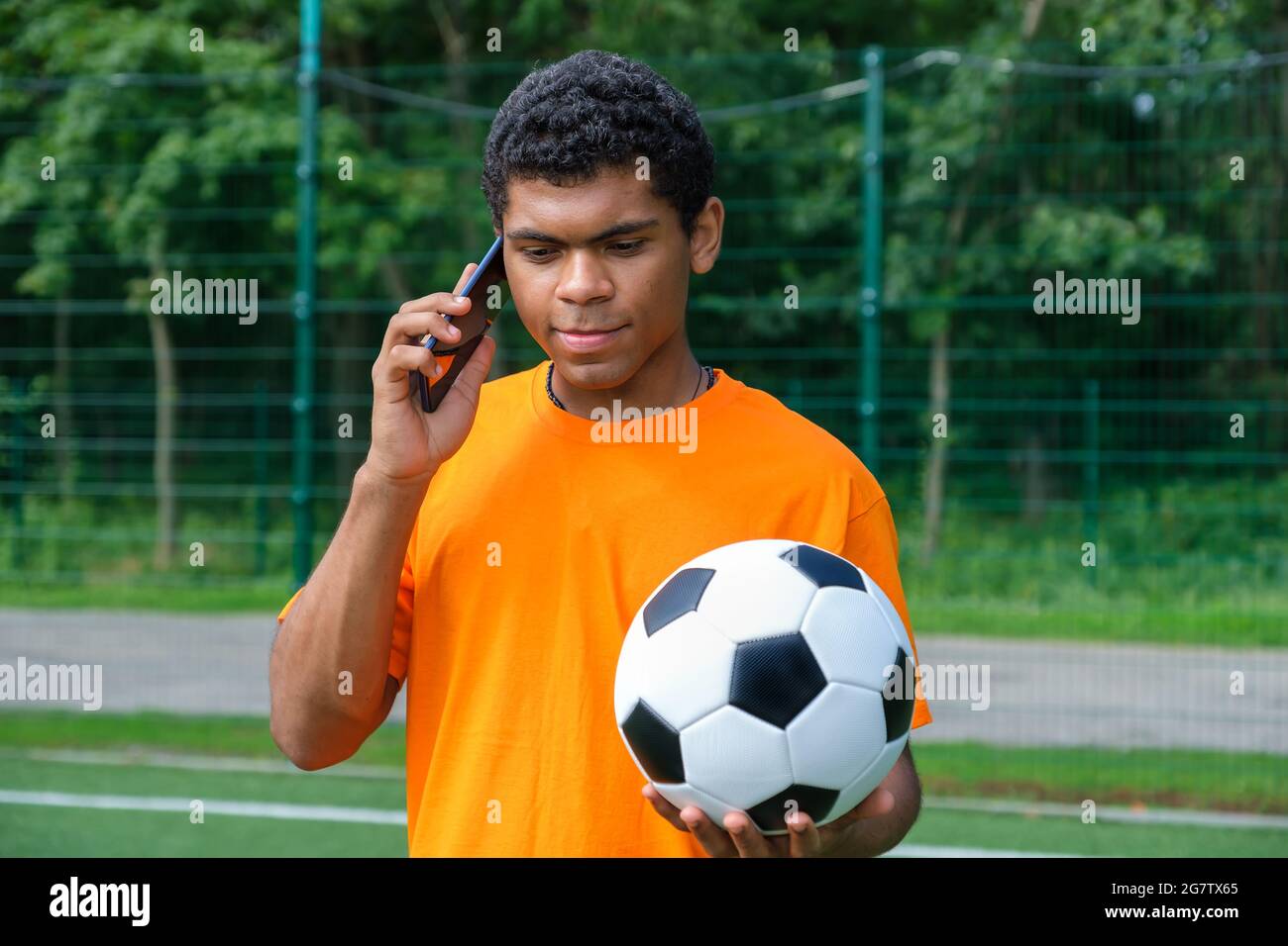Brazilian man holding soccer ball and use smartphone on sports court ...