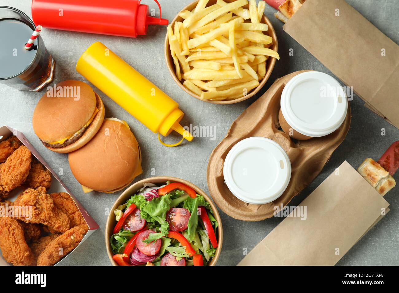 Different fast food on gray textured table Stock Photo - Alamy