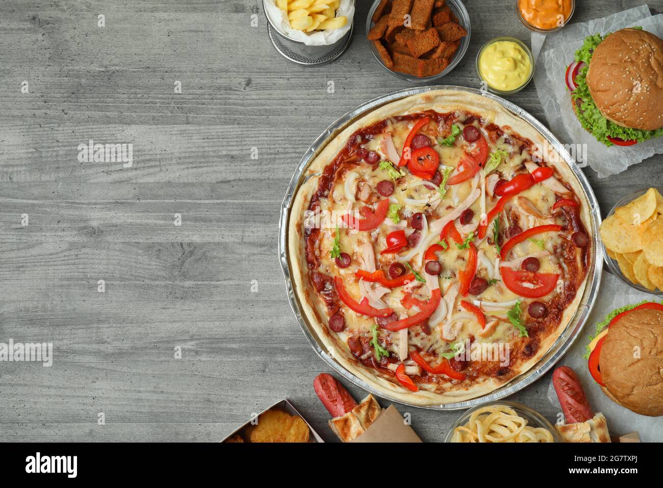 Different fast food on gray textured table Stock Photo - Alamy