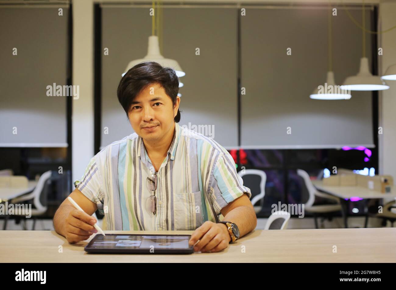 young Asian freelance designer smiling while look at camera against ...