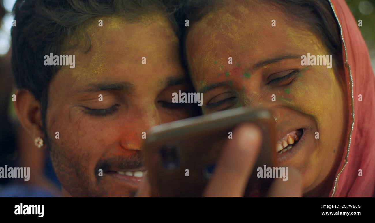 Romantic couple talking on a phone during the Holi Hindu festival of ...