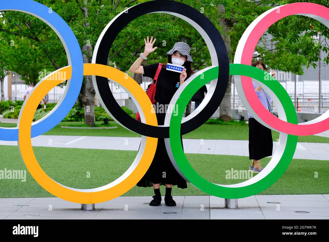 A woman wearing a mask poses for a photo near the Olympic Rings at the ...