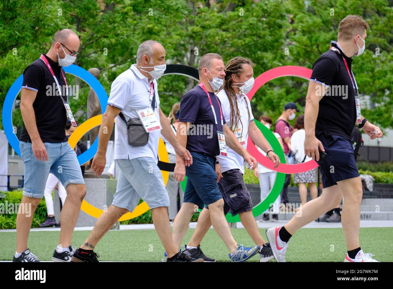 People wearing masks walk past Olympic Rings near the National Stadium ...